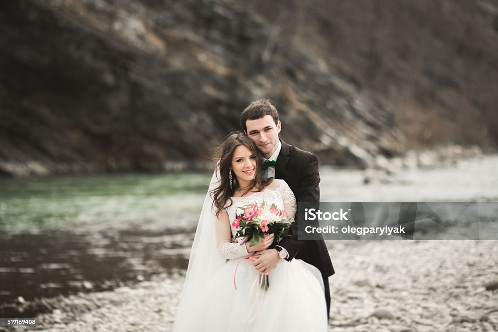 Beautifull Wedding Couple Kissing And Embracing Near River With Stones