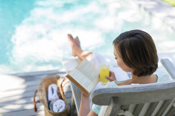 Free Stock Photo of A woman sitting on a deck by a pool reading a book ...