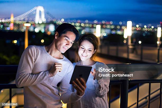 Pasangan Bersandar Pada Pagar Dan Menggunakan Tablet Digital Di Malam