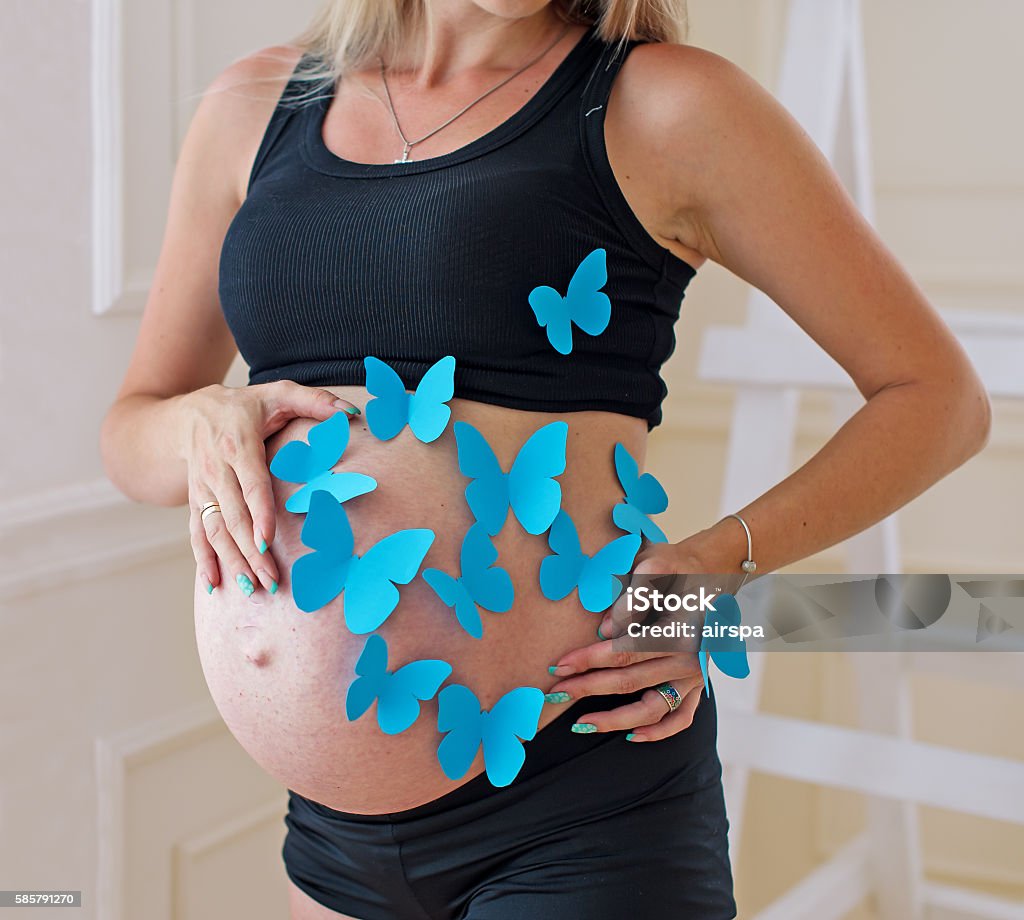 Pregnant Womans Belly With Blue Butterflies Over Nursery Background