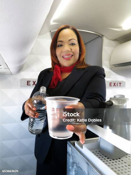 Female Flight Attendant Stewardess Offering Drink To Airline Passenger
