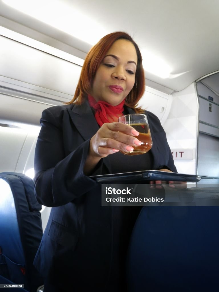 Female Flight Attendant Stewardess Offering Drink To Airline Passenger