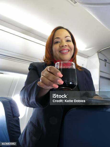 Female Flight Attendant Stewardess Offering Drink To Airline Passenger