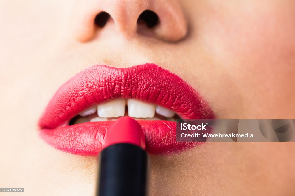 Beautiful Woman Applying Red Lipstick On Lips Against Black Background