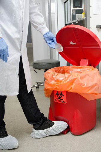 Biohazrd 오렌지 쓰레기통에 플라스틱 폐기물을 떨어지고 실험실 작업자 Bacteriologist에 대한 스톡 사진 및 기타