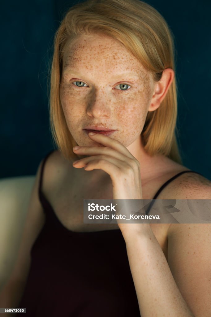 Portrait Of A Beautiful Young Redhead Woman With Freckles On The Body On A Blue Background