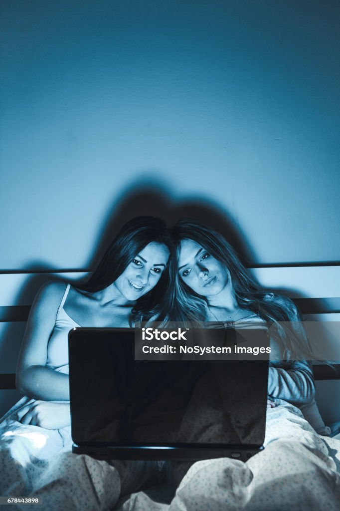 Roommates Lesbian Couple Watching Movie On Laptop At Home In Bedroom