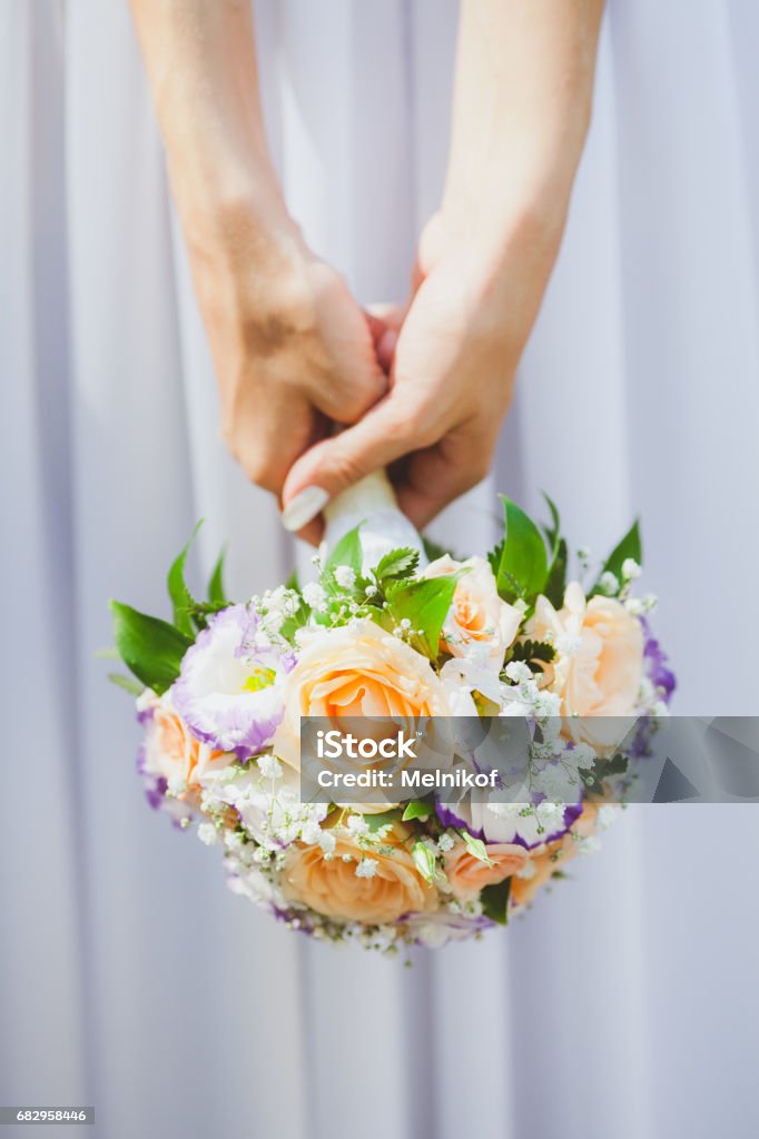 Beautiful Woman In A White Wedding Dress Holding A Flowers Bouquet From