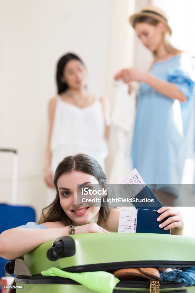 Young Smiling Woman Holding Passports And Tickets While Friends Packing