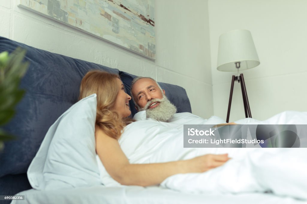 Beautiful Happy Mature Couple Lying Together In Bed And Smiling Each