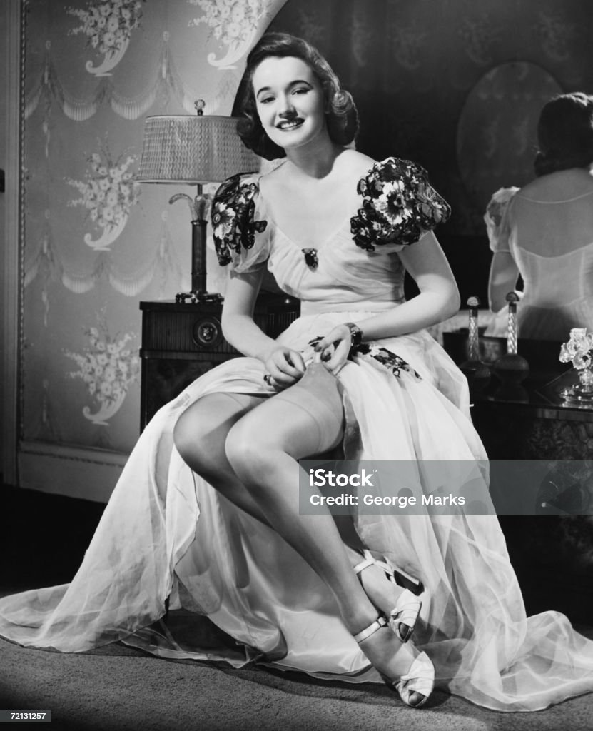 Woman In Evening Gown Putting On Stockings At Vanity Table Portrait