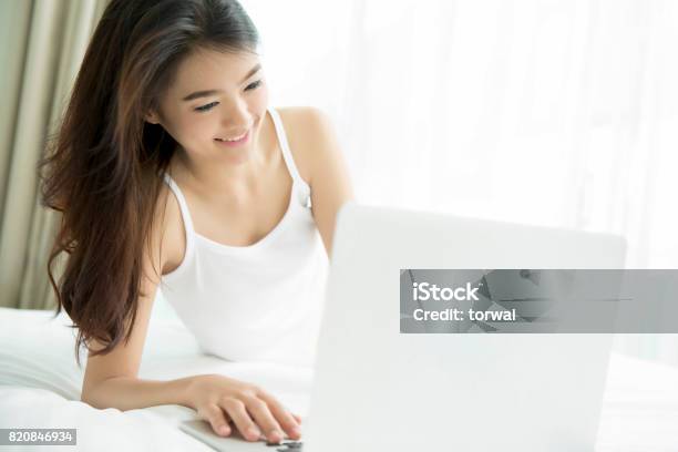 Wanita Asia Menggunakan Laptop Saat Dia Berbaring Di Tempat Tidur Di