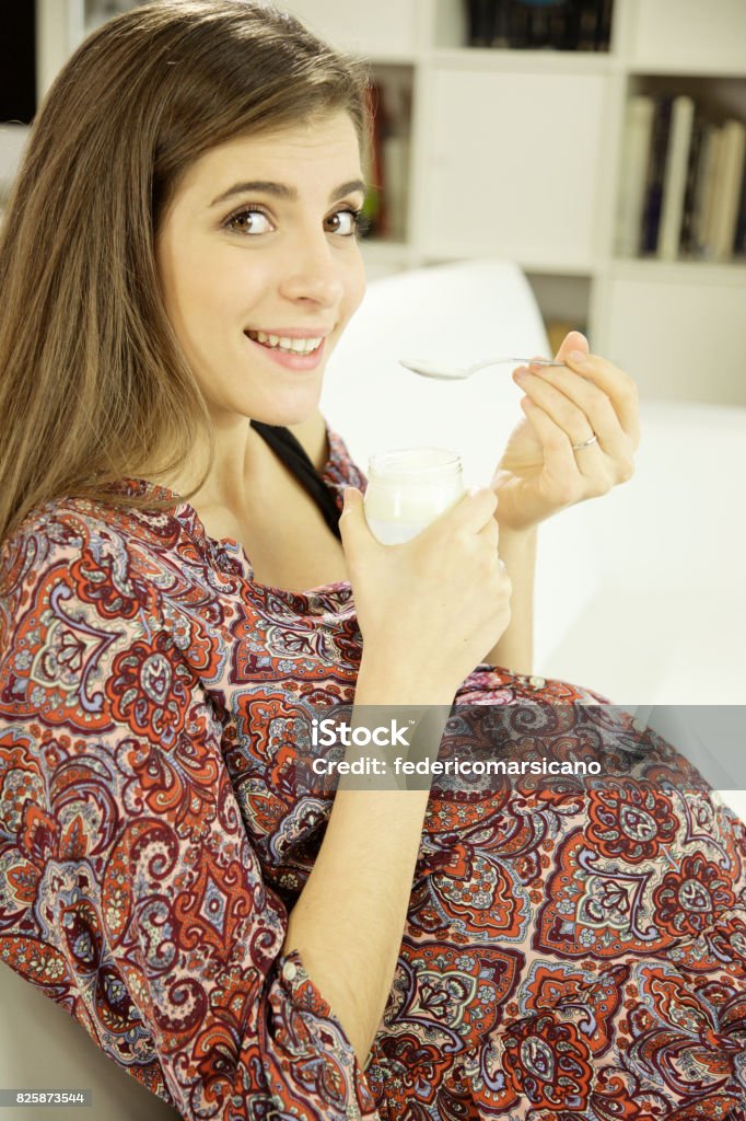 Happy Pregnant Woman Eating Chocolate Ice Cream At Home Looking Camera