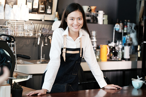 젊은 아시아 여성 바리 스타 서 카페 카운터 배경 중소 기업 소유자 음식 및 음료 산업 개념의 글꼴에서 얼굴을 웃 고 기업