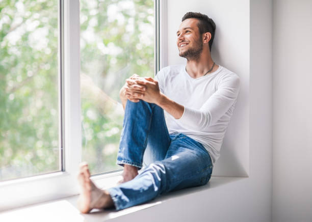 Free Stock Photo of Man Sitting on Window Sill Looking Out at City ...
