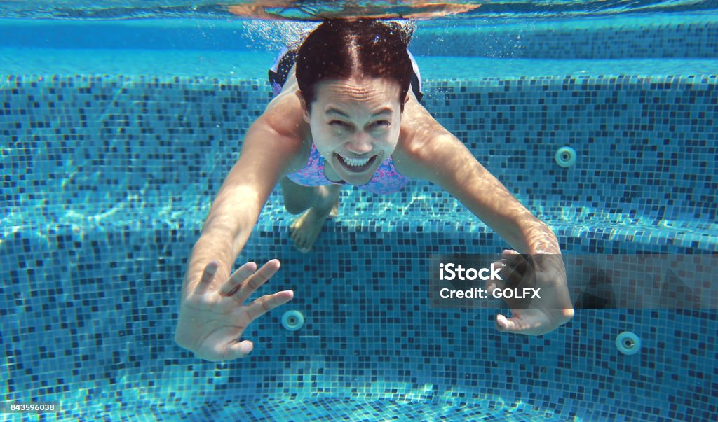 Underwater Shot Of Young Woman Diving Into The Swimming Pool Stock