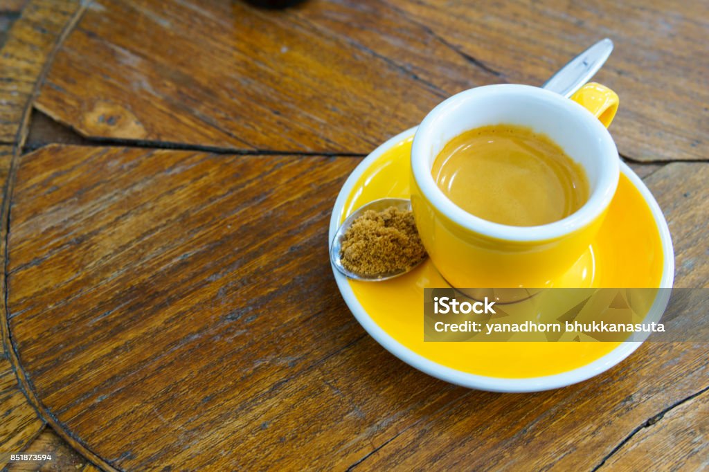 Ristretto 또는 에스프레소 커피 오래 된 나무 테이블에 갈색 설탕의 숟가락으로 노란 컵에 총 텍스트에 대 한 공간을 복사
