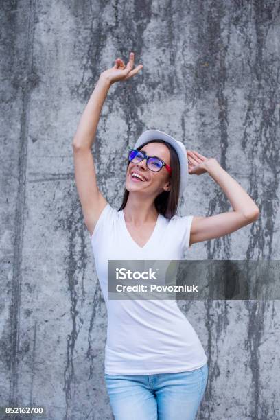Hipster 안경 및 모자 콘크리트 벽 근처에 행복 한 매력적인 젊은 여자 20 29세에 대한 스톡 사진 및 기타 이미지