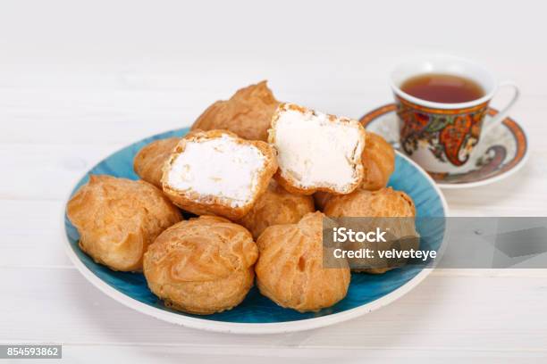 Profiteroles 신선한 크림 퍼프 페이스 트리 크림 흰색 접시에 흰색 나무 바탕에 페이 즐 리 디자인으로 차 한 잔으로