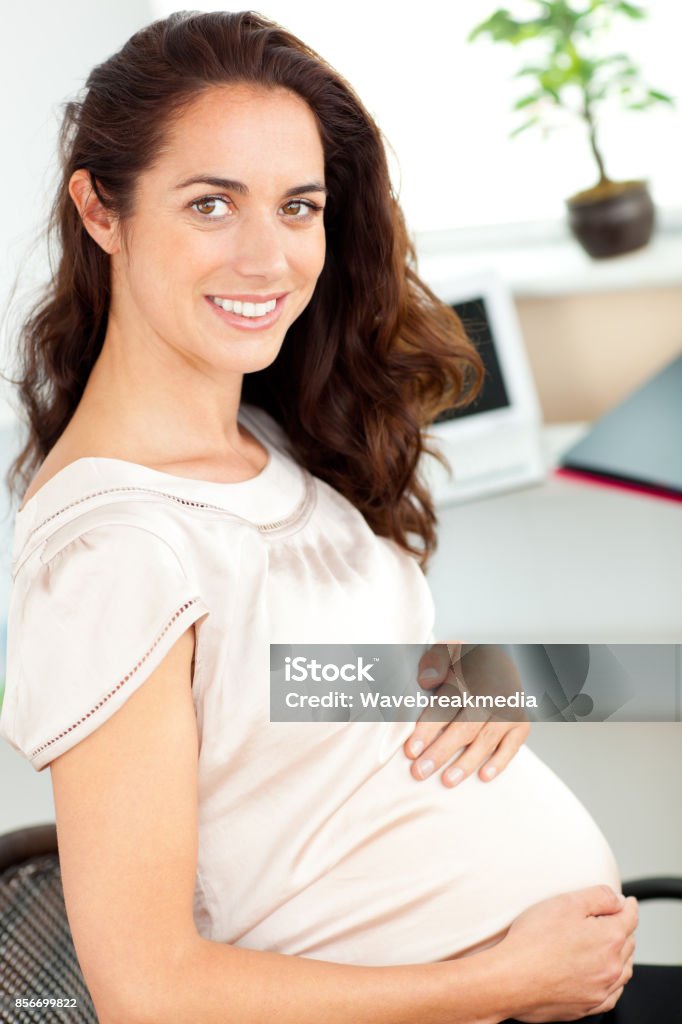 Pregnant Businesswoman Smiling At The Camera Sitting At Her Desk Stock
