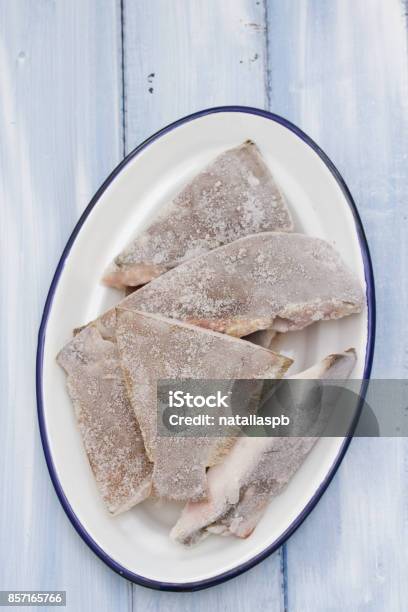 Ikan Beku Dalam Hidangan Putih Dengan Latar Belakang Kayu Biru Foto