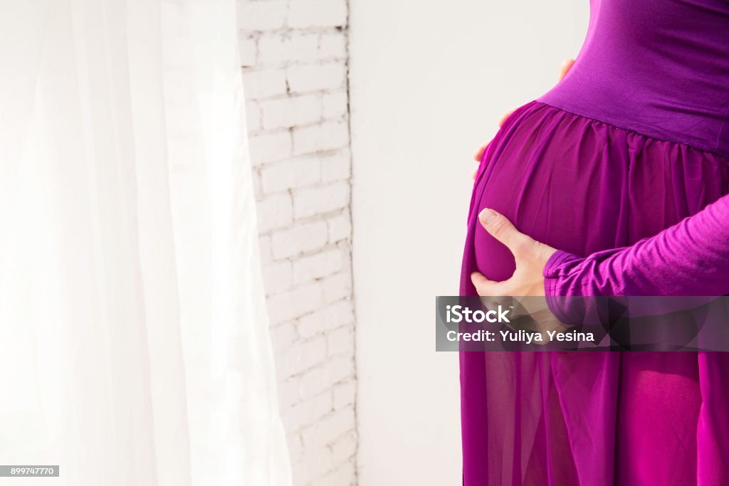 Photo Libre De Droit De Femme Enceinte En Robe Violette A Mis Ses Mains Sur Son Ventre Banque D