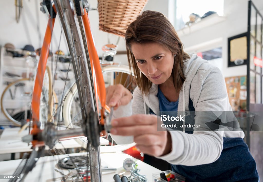 Latin American Manual Worker At A Bicycle Store Adjusting A Wheel To A ... Latin American Manual Worker At A Bicycle Store Adjusting A Wheel To A ...