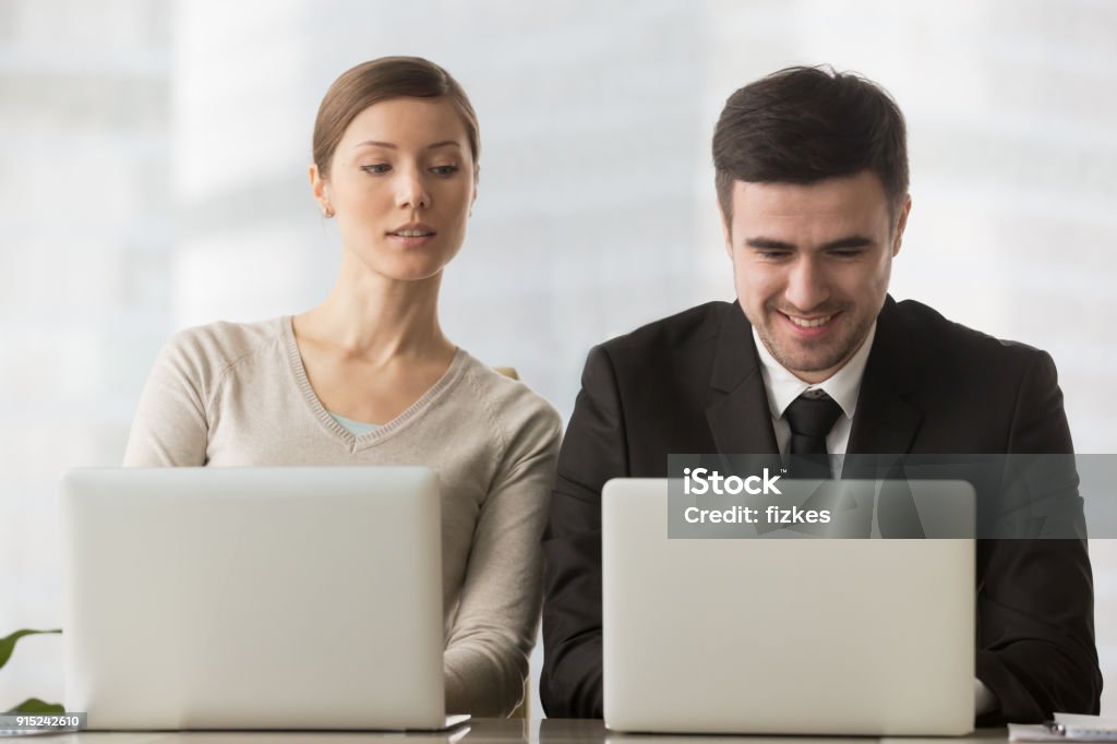 Interested Curious Businesswoman Looking At Businessman Laptop Screen