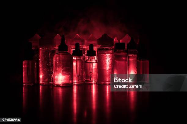 Vape 개념입니다 구름과 어두운 배경에 Vape 액체 병 연기 조명 효과 Cartomizer에 대한 스톡 사진 및 기타 이미지