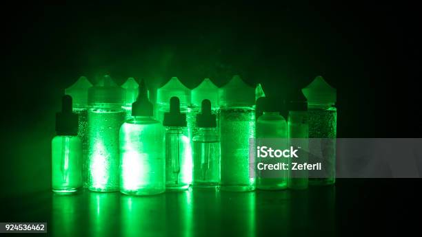 Vape 개념입니다 구름과 어두운 배경에 Vape 액체 병 연기 조명 효과 Cartomizer에 대한 스톡 사진 및 기타 이미지