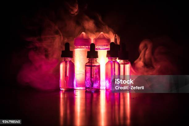 Vape 개념입니다 구름과 어두운 배경에 Vape 액체 병 연기 조명 효과 Cartomizer에 대한 스톡 사진 및 기타 이미지