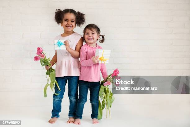 Dua Gadis Kecil Multietnis Memegang Hadiah Dan Tulip Untuk Hari Ibu ... Dua Gadis Kecil Multietnis Memegang Hadiah Dan Tulip Untuk Hari Ibu ...