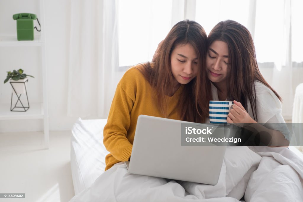 Asia Lesbian Lgbt Couple Sitting On Bed Hug And Using Laptop Computer