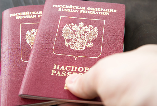 Travel Concept Male Hand Holding Red Passport On The Wooden Background
