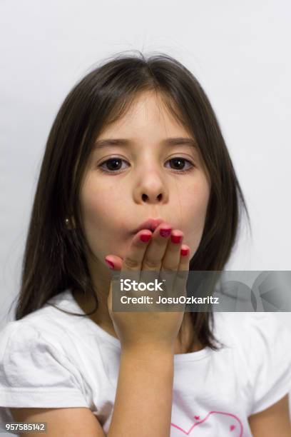 Gadis Kecil Yang Lucu Dengan Tangan Di Mulut Meniup Ciuman Ke Kamera Di