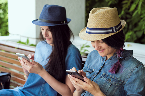 Dua Gadis Duduk Di Bangku Di Taman Dan Melihat Smartphone Menggunakan