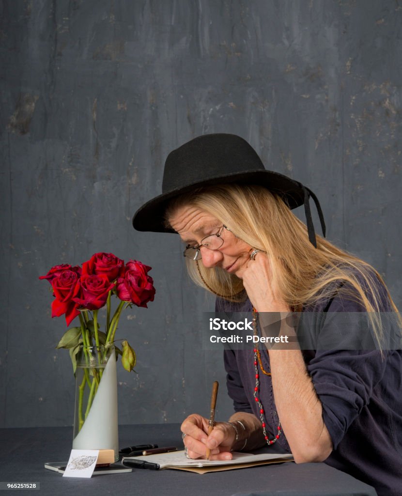 Mature Woman With Glasses Writes At Her Deskshe Concentrates On Her